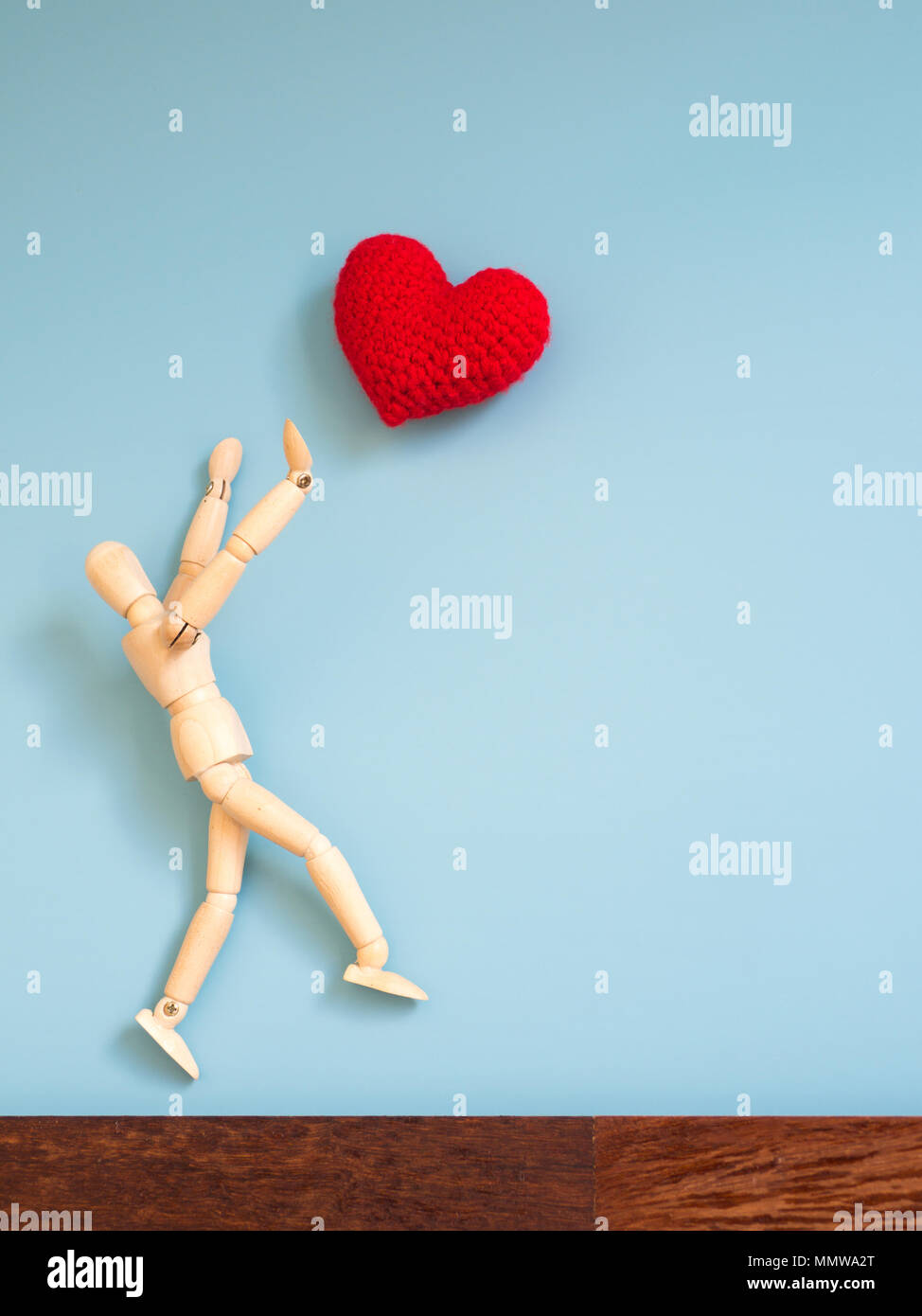 Wooden puppet jumping from the wooden floor in the air to catch the red ...