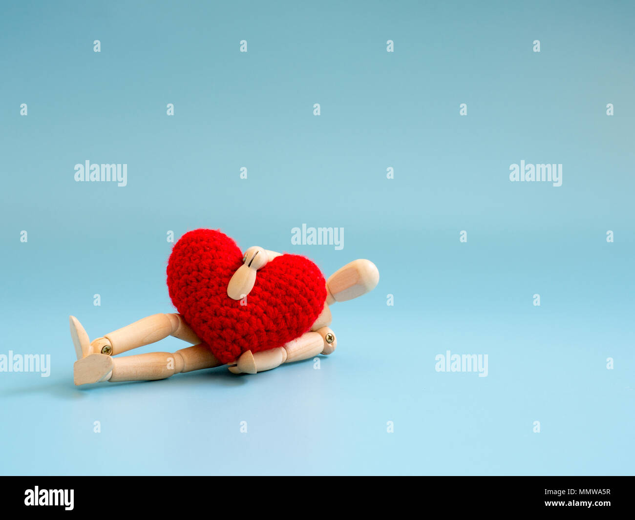 Wooden puppet hugging red heart and fall down on the floor. copy space ...