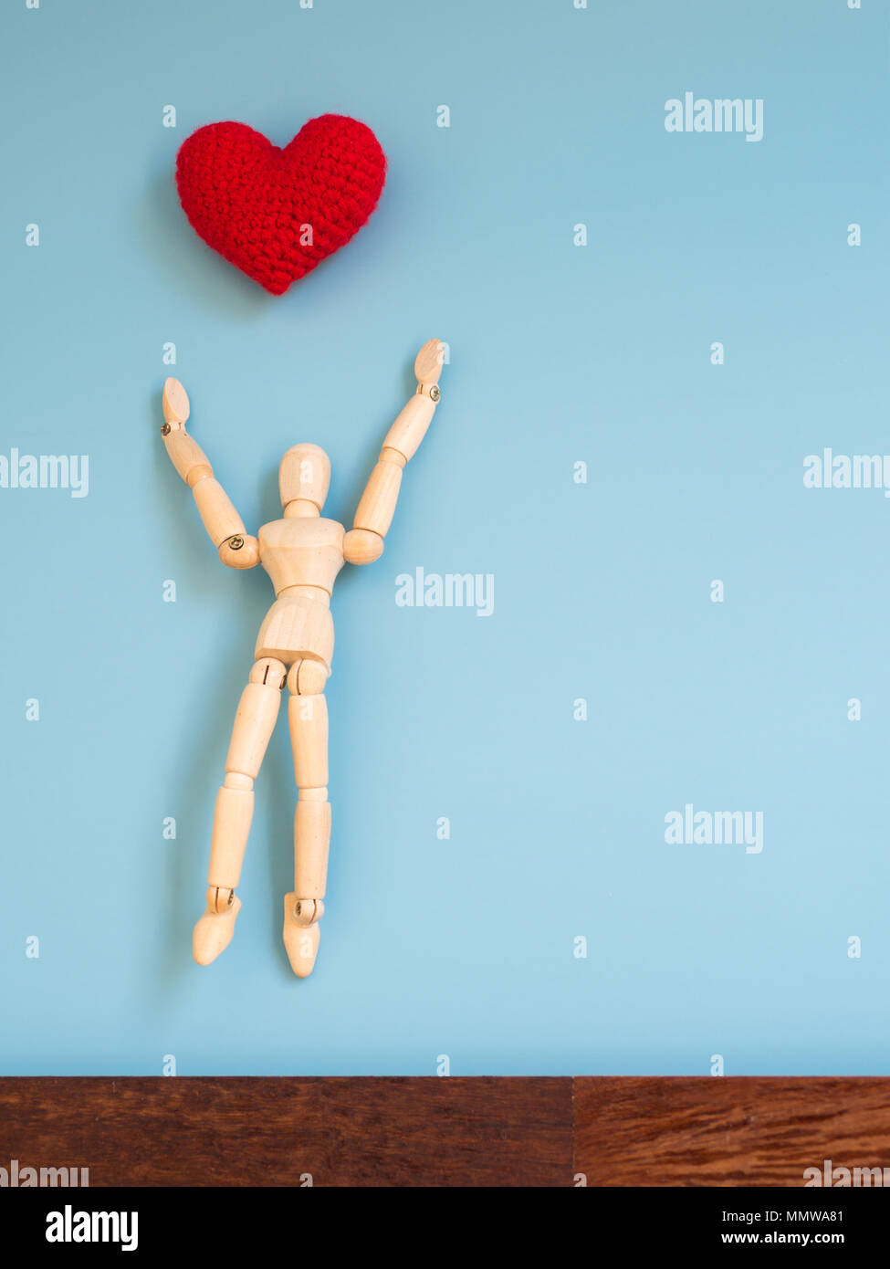 Wooden puppet jumping from the wooden floor in the air to catch the red ...