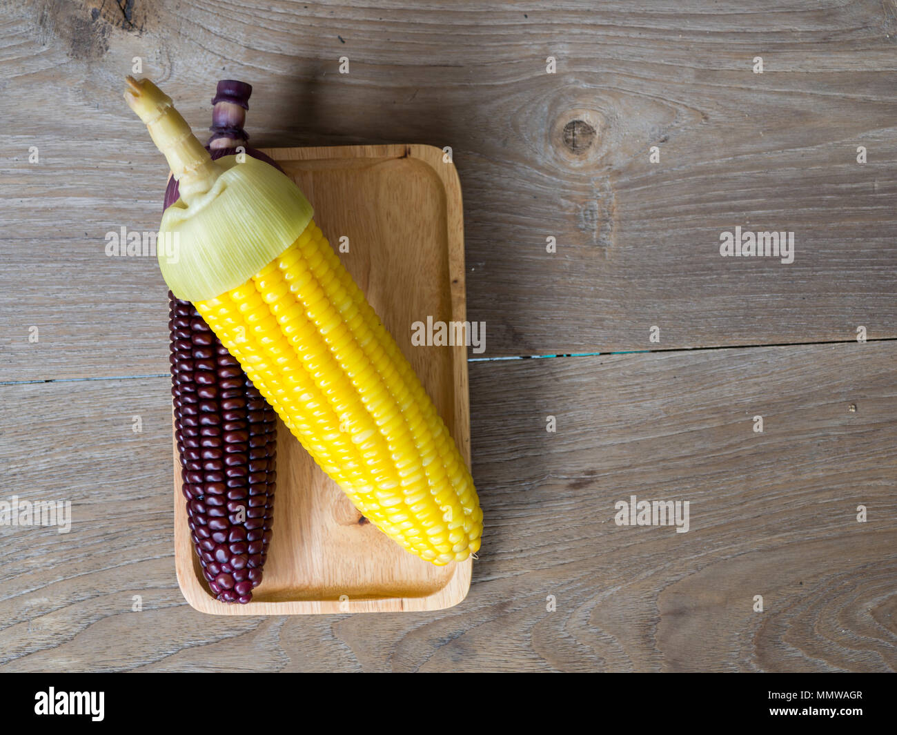 The corn stalks boiled and delicious on the wooden dish and the dish on ...