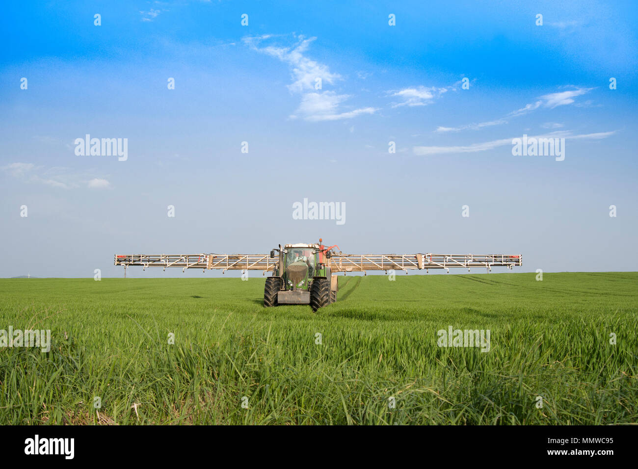 Tractor spraying wheat field with sprayer Stock Photo - Alamy