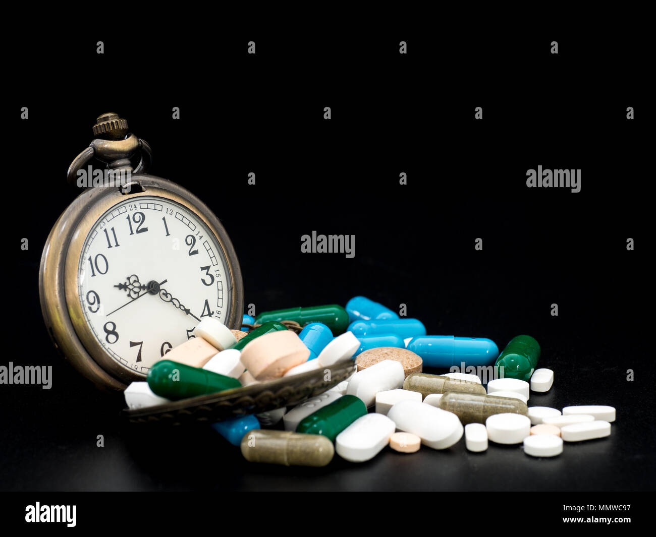 Antique clock on multicolored of drug and capsule is on the black ...