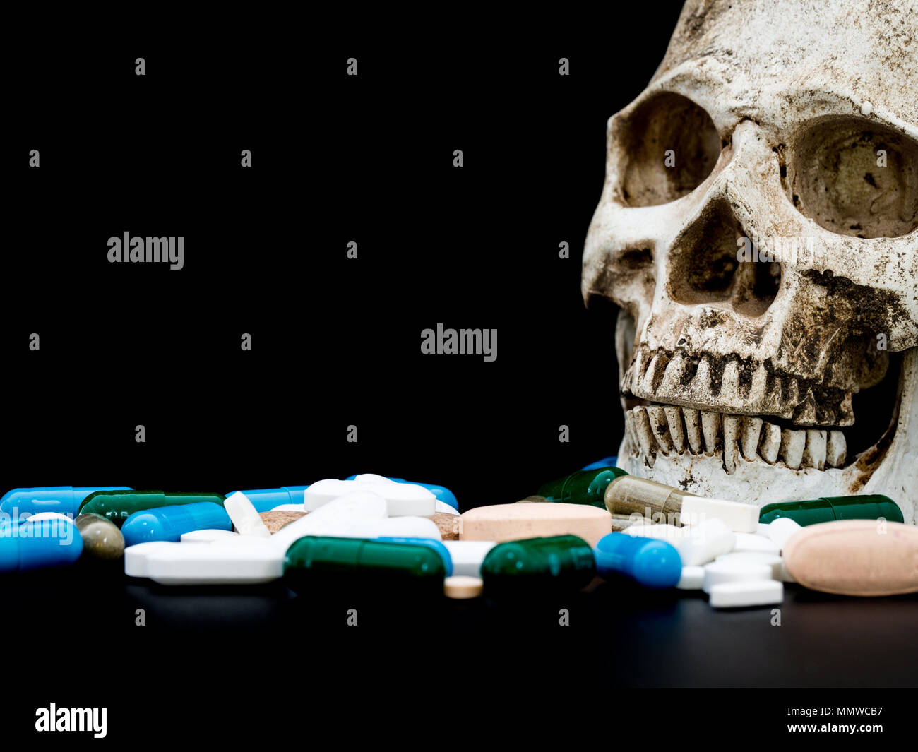 Human skull on multicolored of drug and capsule is on the black ...