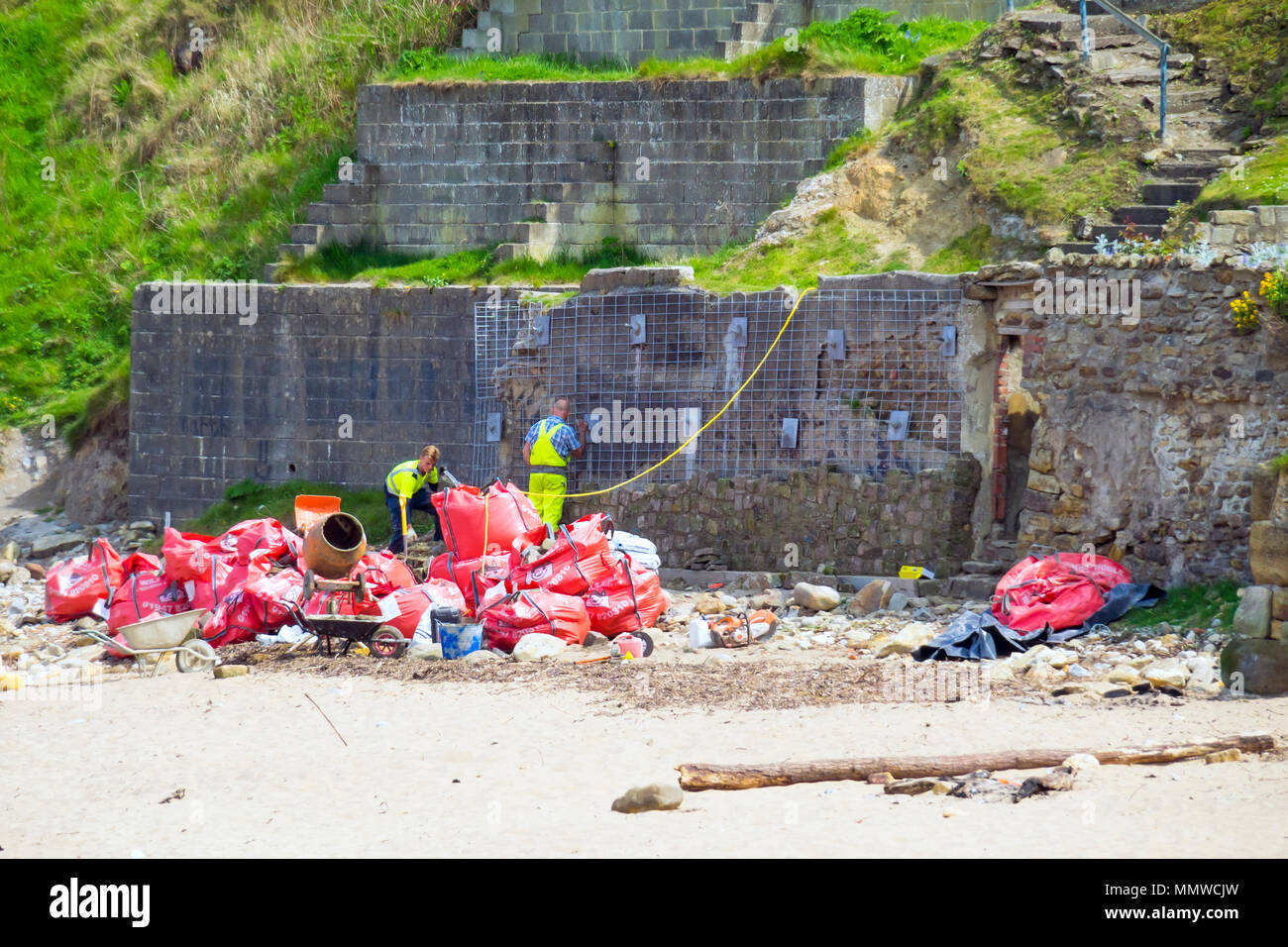 Workmen on Tate Hill beach Whitby repairing a retaining wall with ...