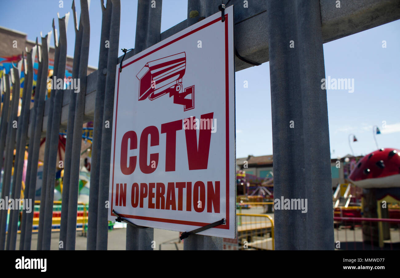 White CCTV sign with red lettering and red border, mounted on a grey ...