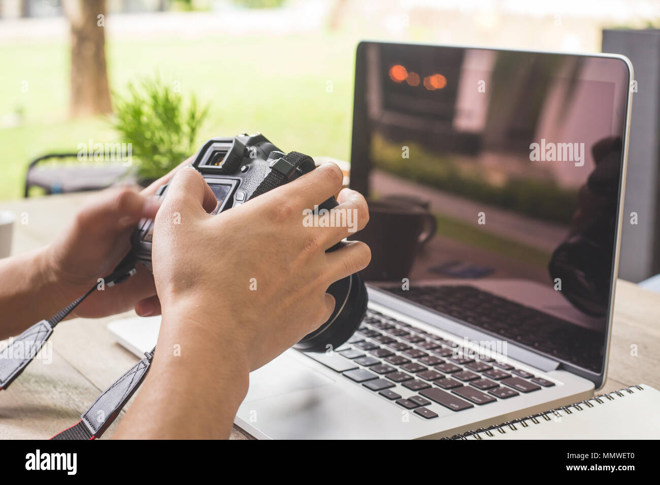 Man hands hand holding camera and using laptop computer in coffee shop ...
