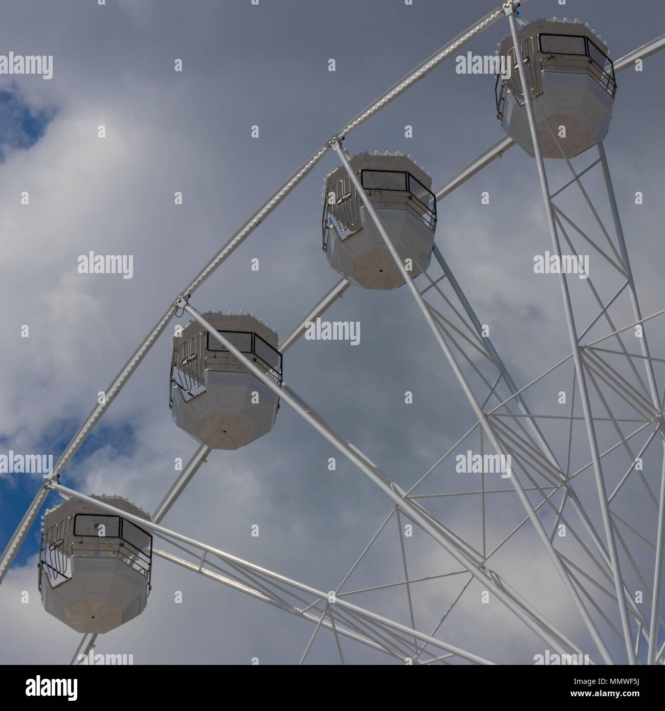Low angled closeup of four empty gondolas on a white Ferris Wheel near ...