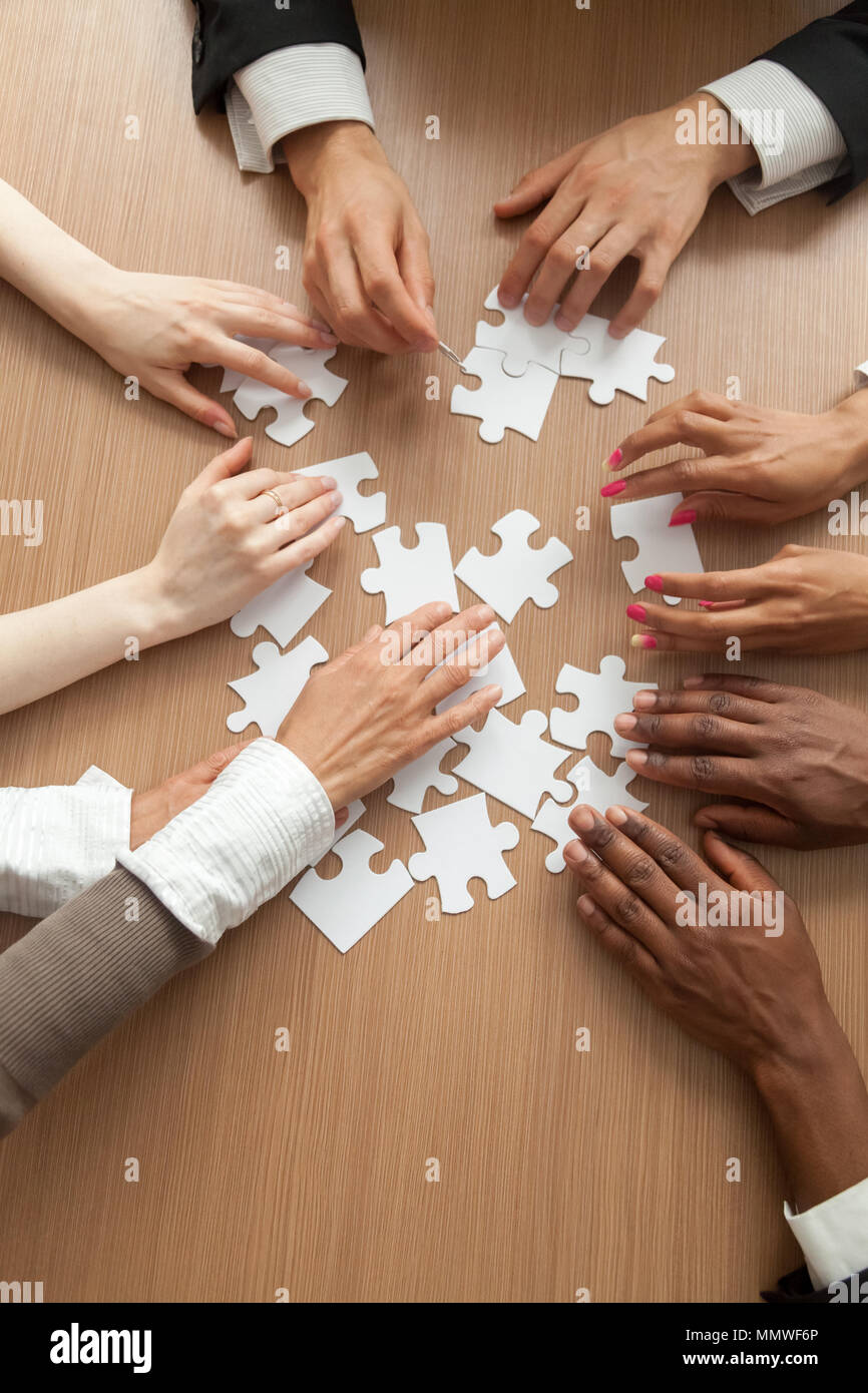 Multiracial business team assembling puzzle together, vertical c Stock ...