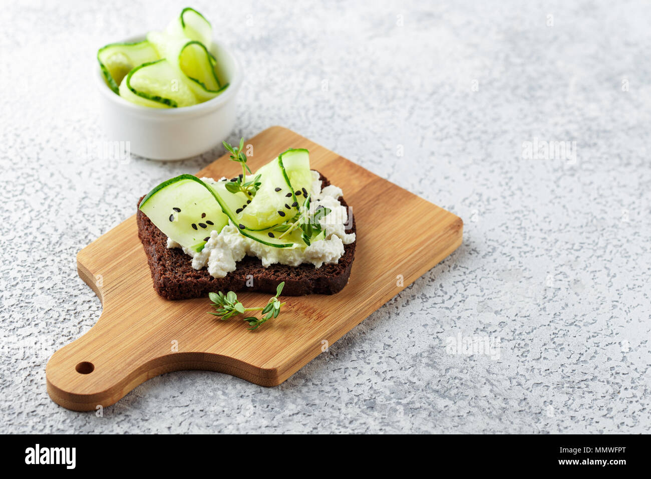 Toasts of rye bread with ricotta, cucumber and black sesame on a grey ...