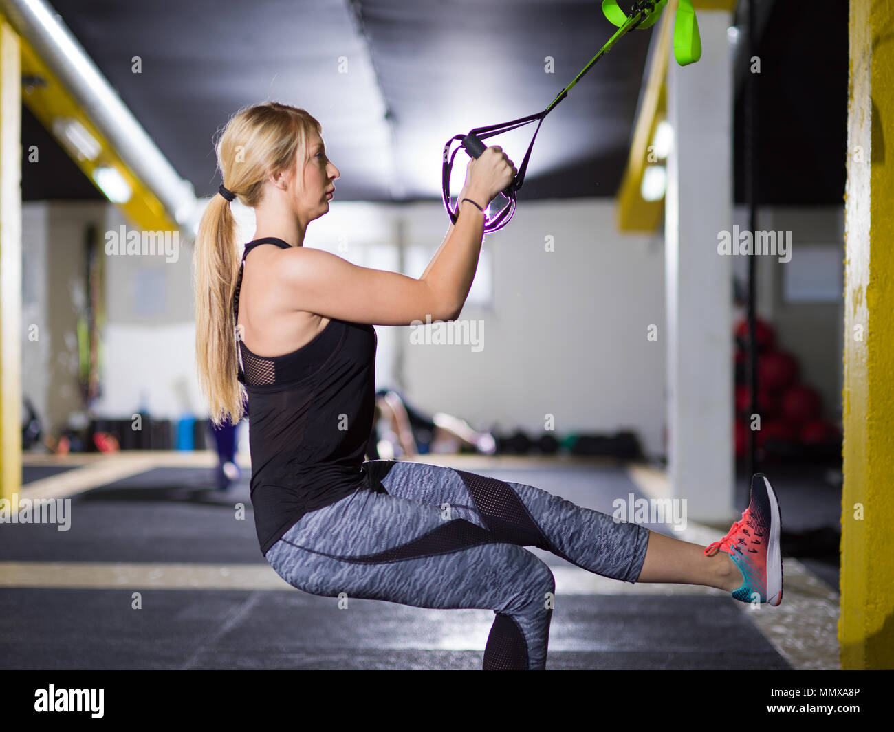 young athlete woman working out pull ups with gymnastic rings at the ...