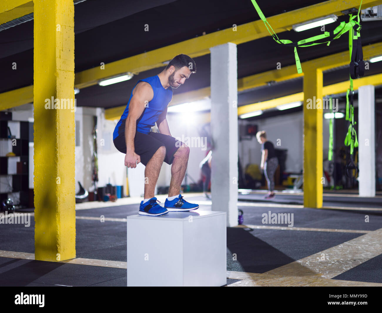 young athletic man training jumping on fit box at crossfitness gym ...
