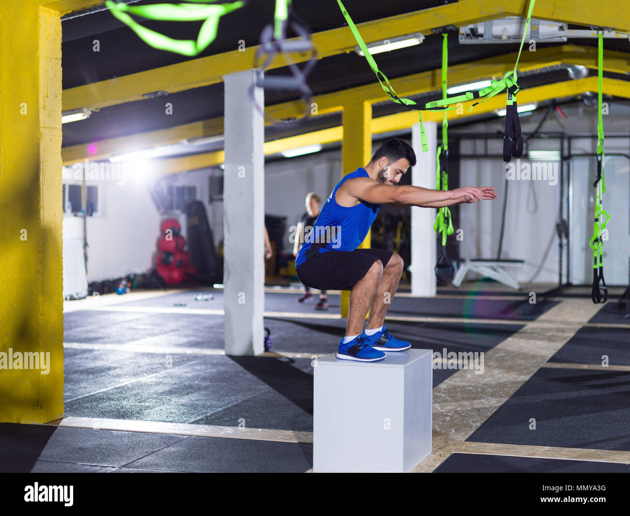 young athletic man training jumping on fit box at crossfitness gym ...