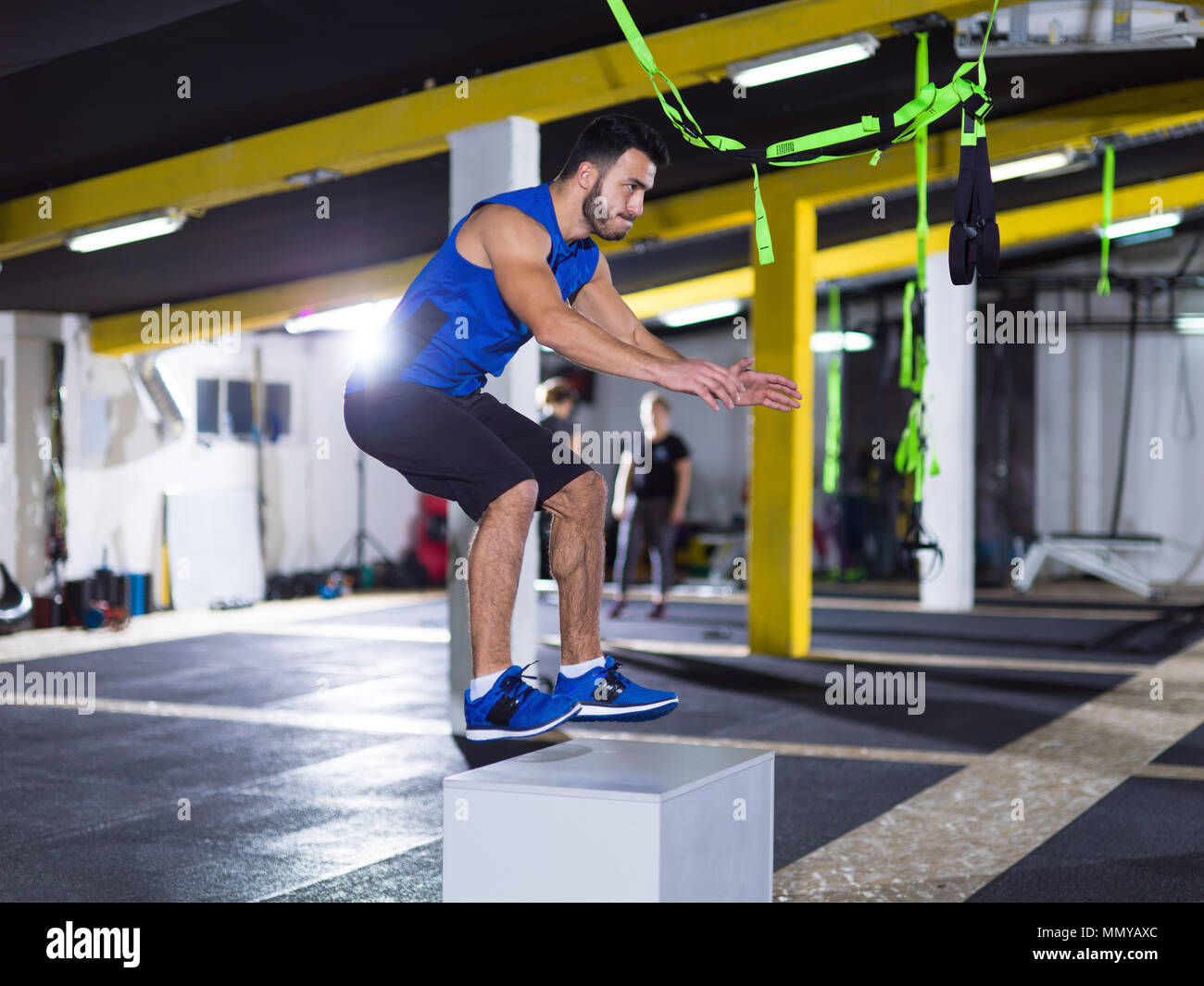 young athletic man training jumping on fit box at crossfitness gym ...