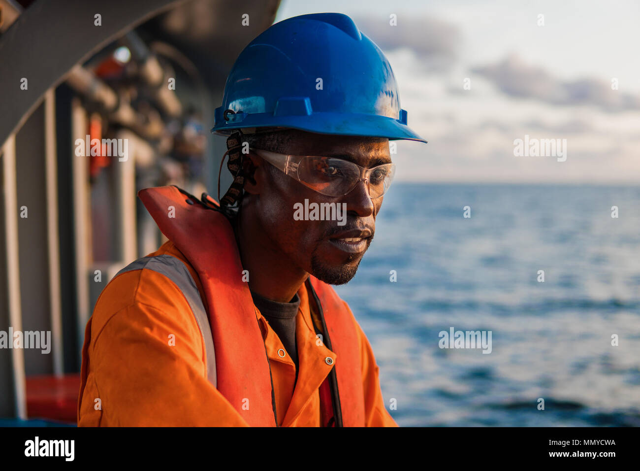 Tired Seaman AB or Bosun on deck of vessel or ship , wearing PPE ...