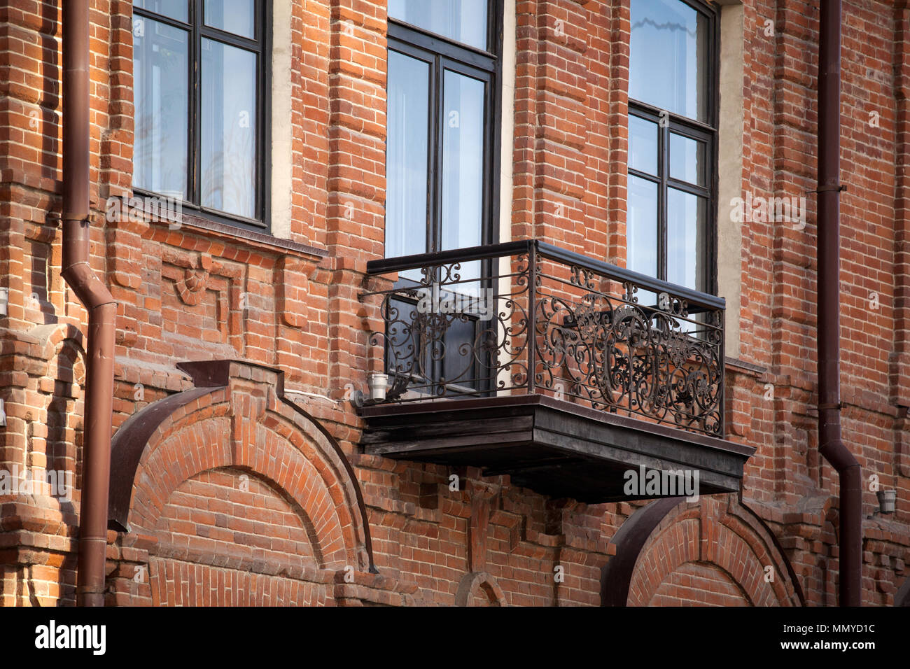 A close-up of a metal balcony of an old brick house. The facade of the ...