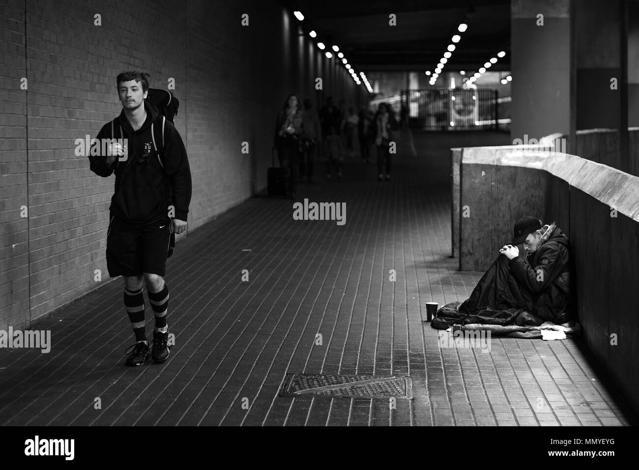 The sight of a homeless man slumped against a wall while busy commuters ...