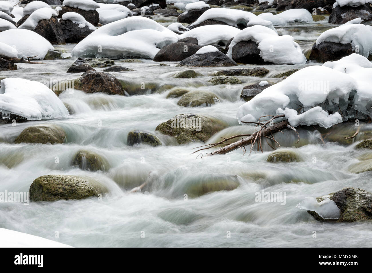River flows through a wintery scene with snow ice and a tree Stock ...