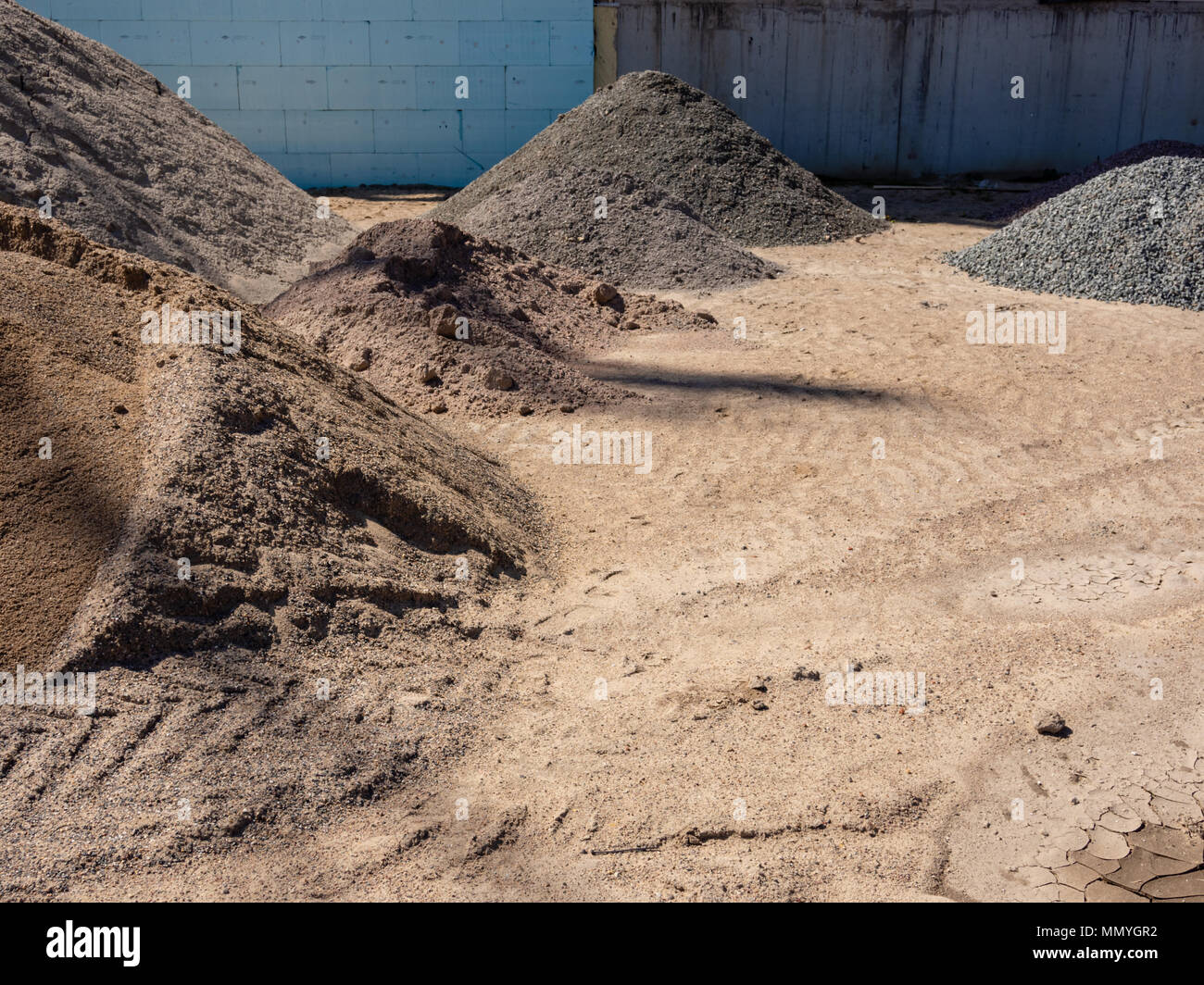 Heaps of sand and stones of different colour and size at sandy ground ...