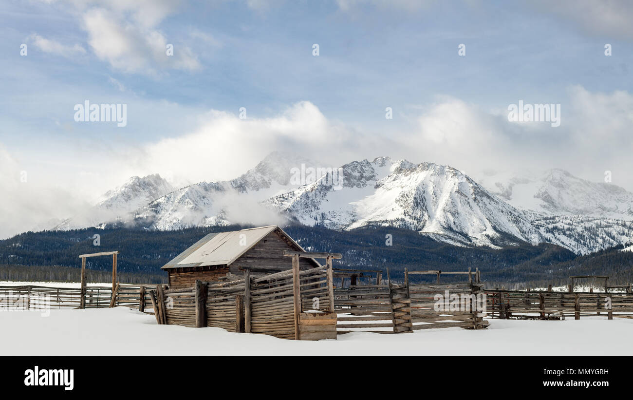 Classic western corral with log fence and snow covered mountain range ...