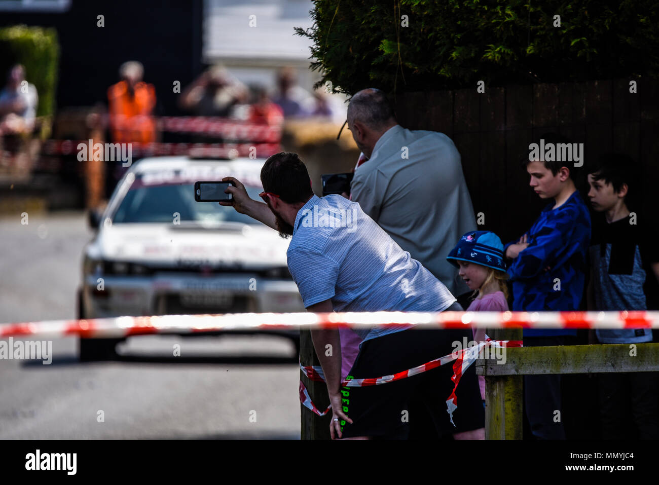 Spectator taking mobile phone camera photograph of car racing in the ...