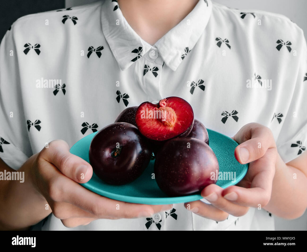 Fresh ripe plums Girl is holding blue plate with plums in her hands ...