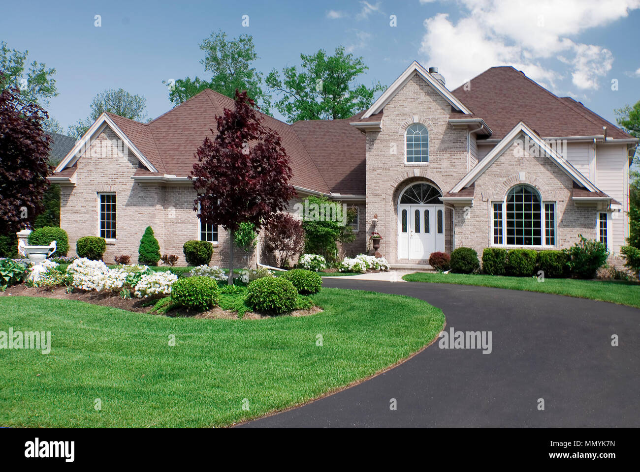 Beautiful and large brown brick home featuring a complex roof design ...