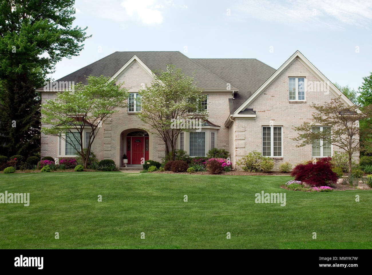 Beautiful biege brick home featuring colorful landscaping Stock Photo ...