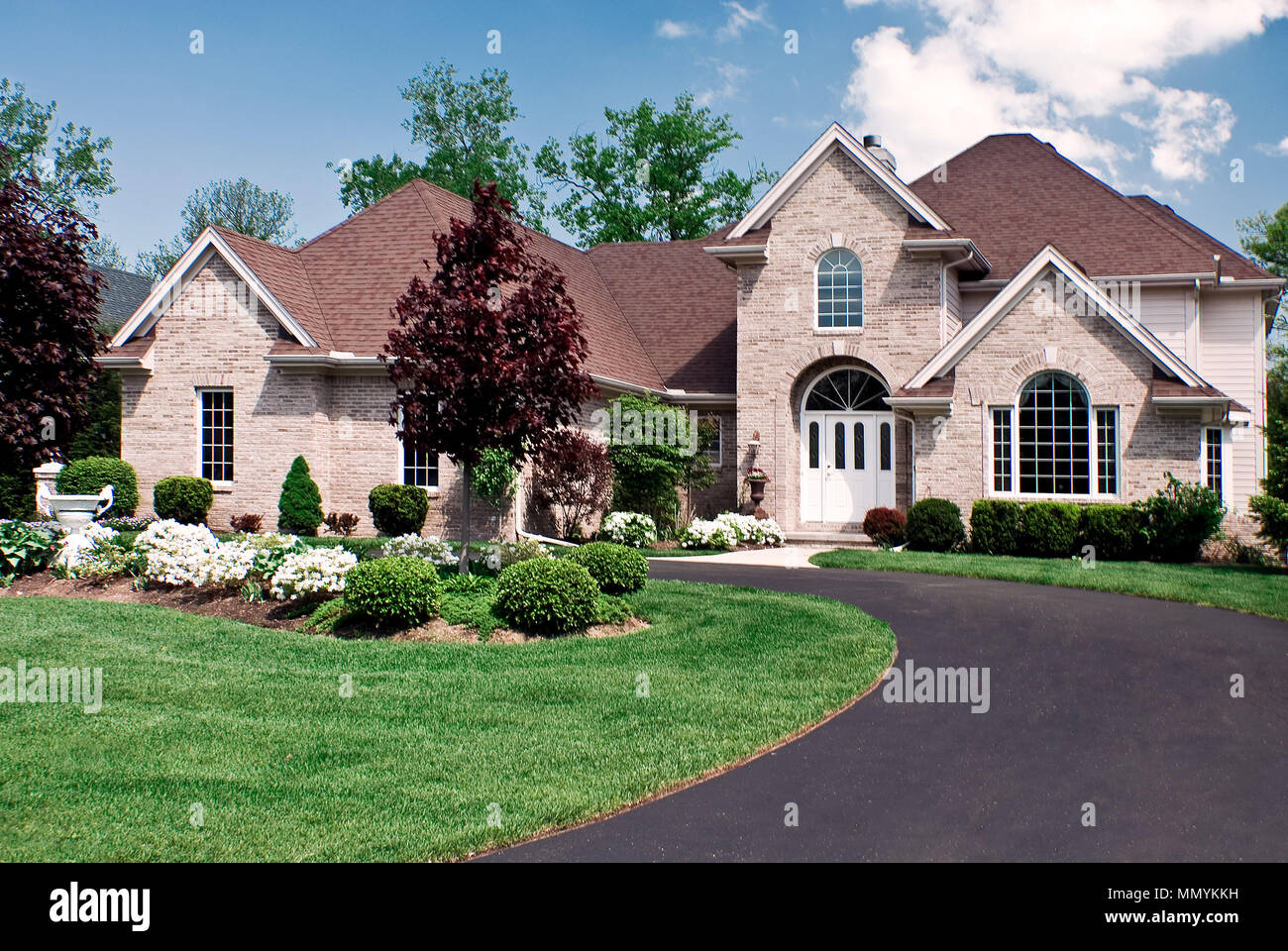 Beautiful and large brown brick home featuring a complex roof design ...