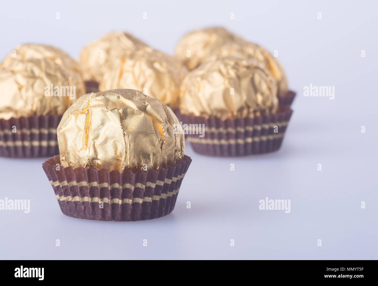 Chocolate ball in a gold foil paper on a background Stock Photo - Alamy