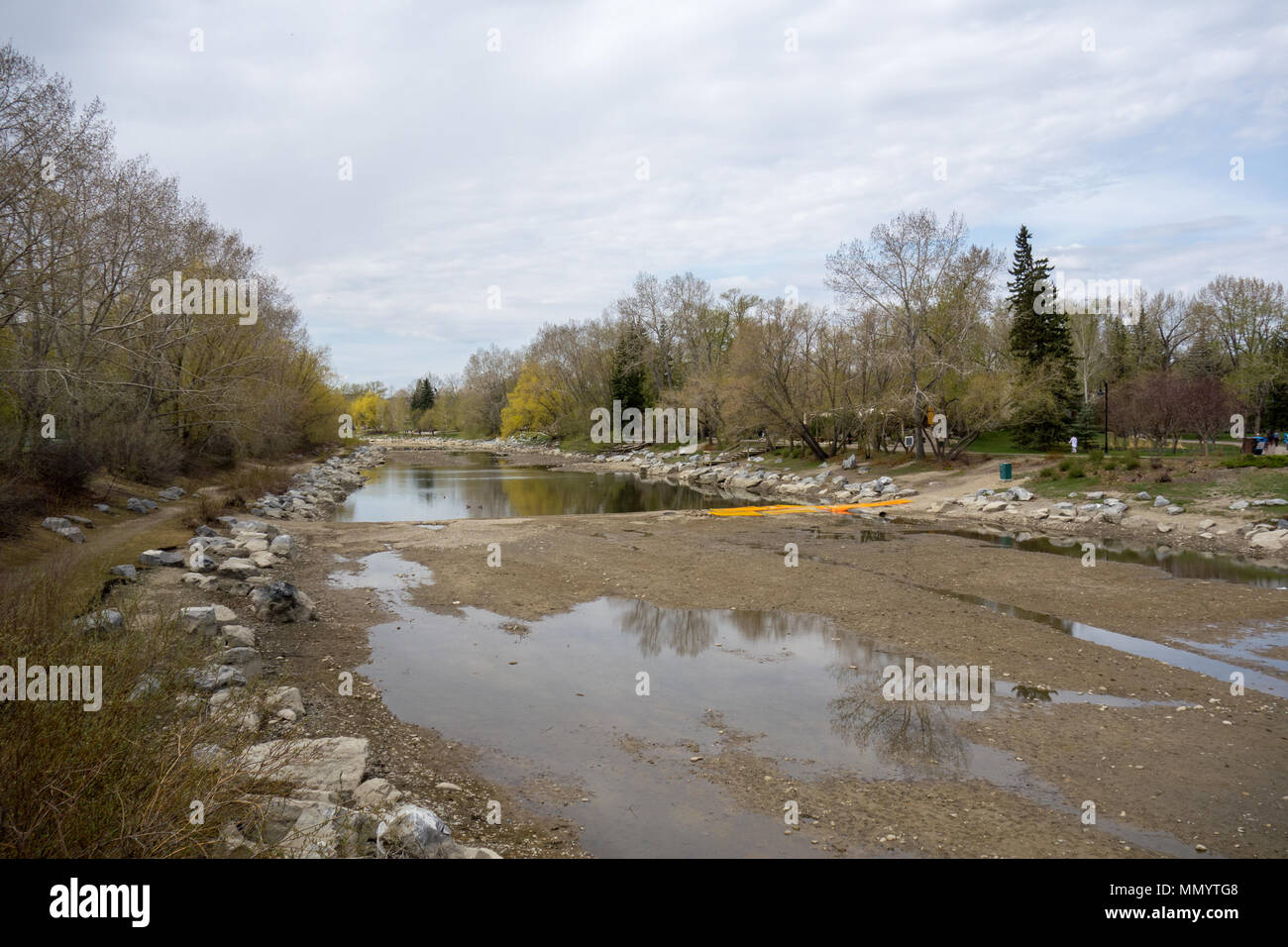 A nearly dry Bow River dammed running between Princes Island Park and ...