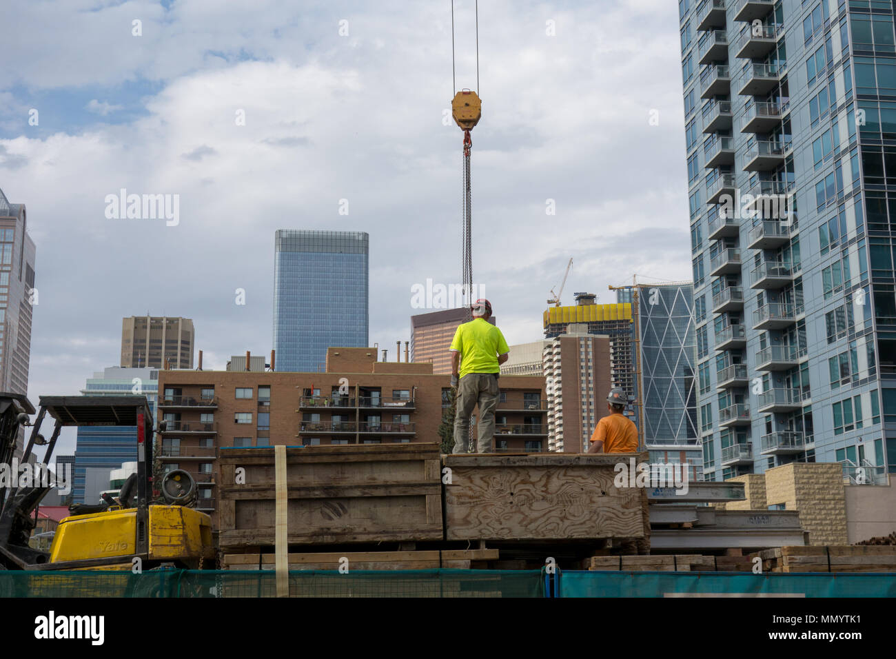 Construction workers waiting to attach a new load of materials for a ...