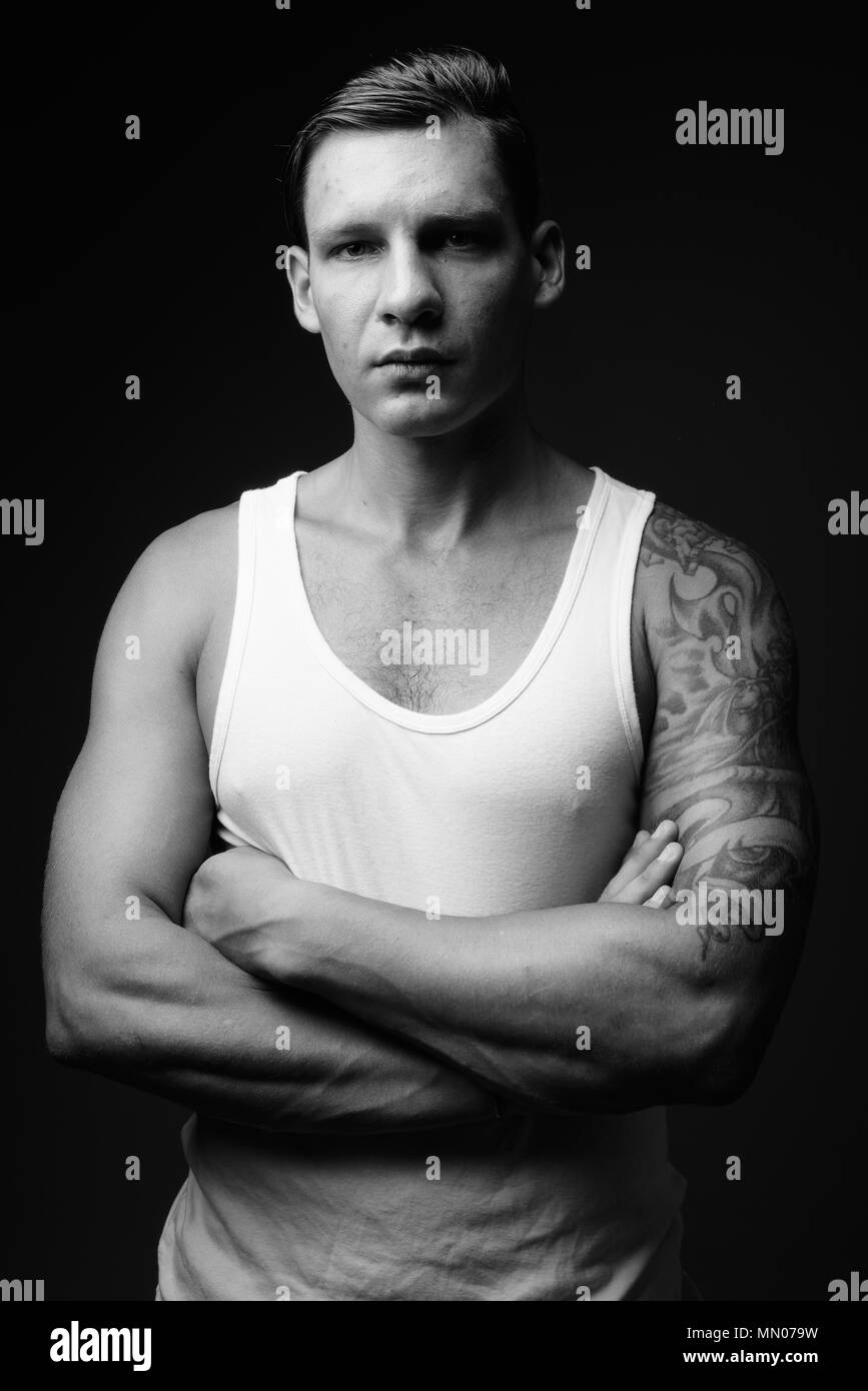 Muscular man wearing white tank top against black background in Stock ...