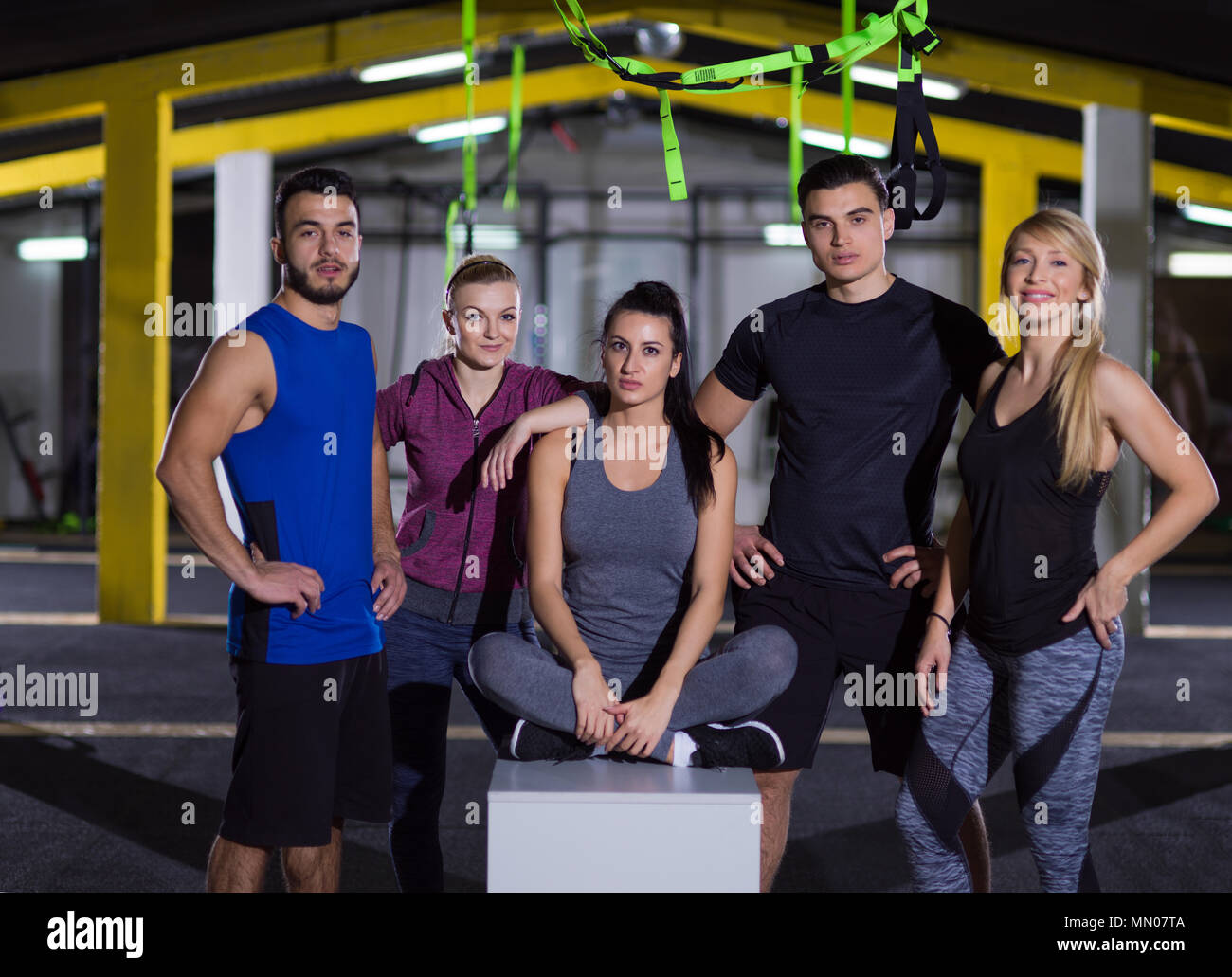 portrait of young healthy athletic people training jumping on fit box ...