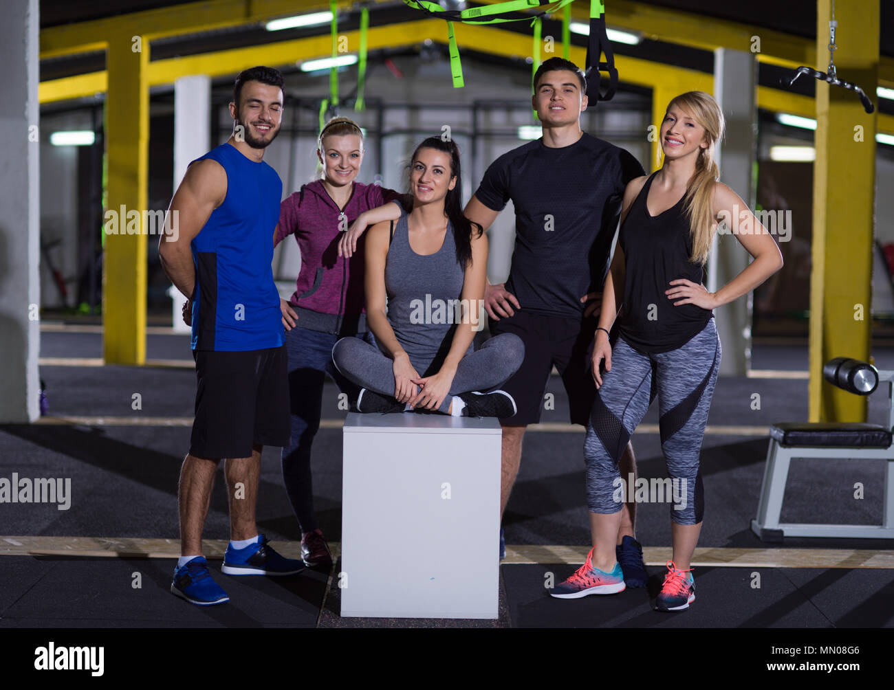 portrait of young healthy athletic people training jumping on fit box ...
