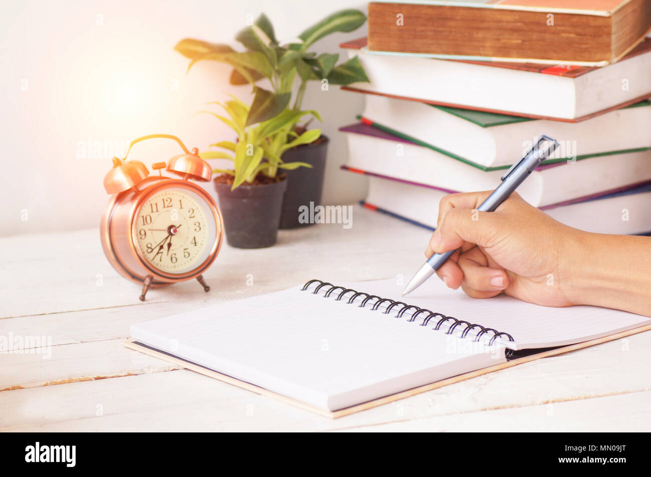 hand writing with books and clock on desk Stock Photo - Alamy