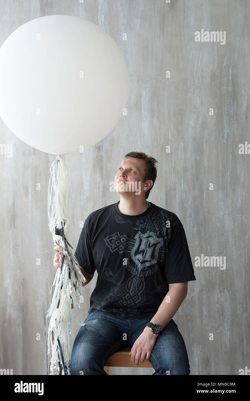 A man holding an inflatable ball on a gray background. Big ball, brutal ...