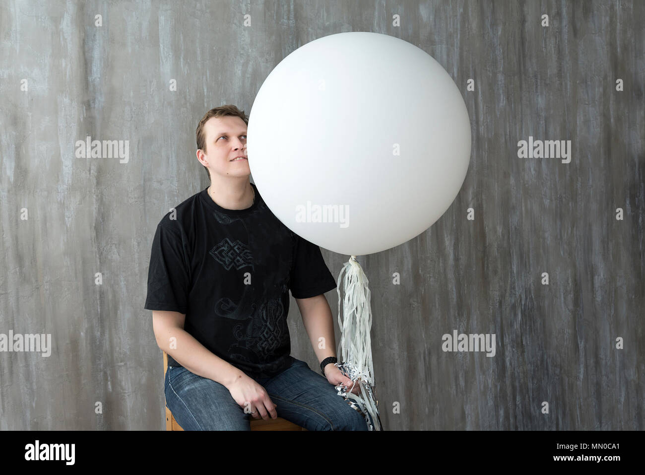 A man holding an inflatable ball on a gray background. Big ball, brutal ...