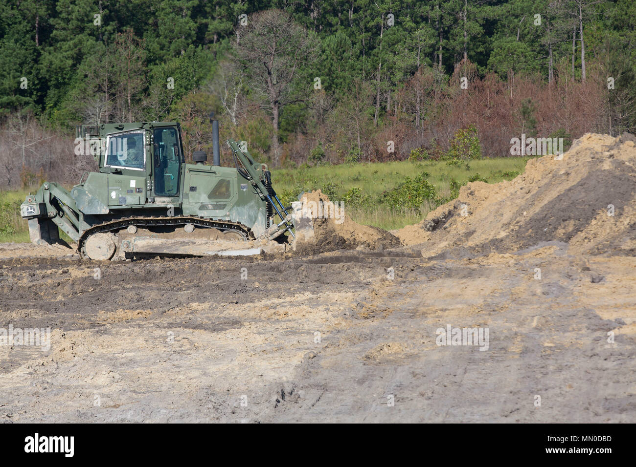 A Marine uses a Medium Crawler Tractor Bulldozer to push dirt into a ...