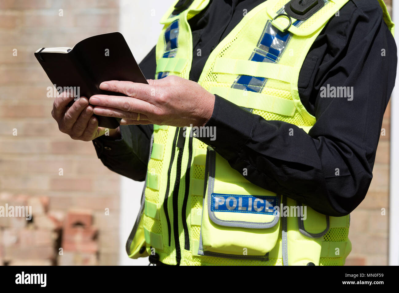 Police officer reading from a black note book Stock Photo - Alamy