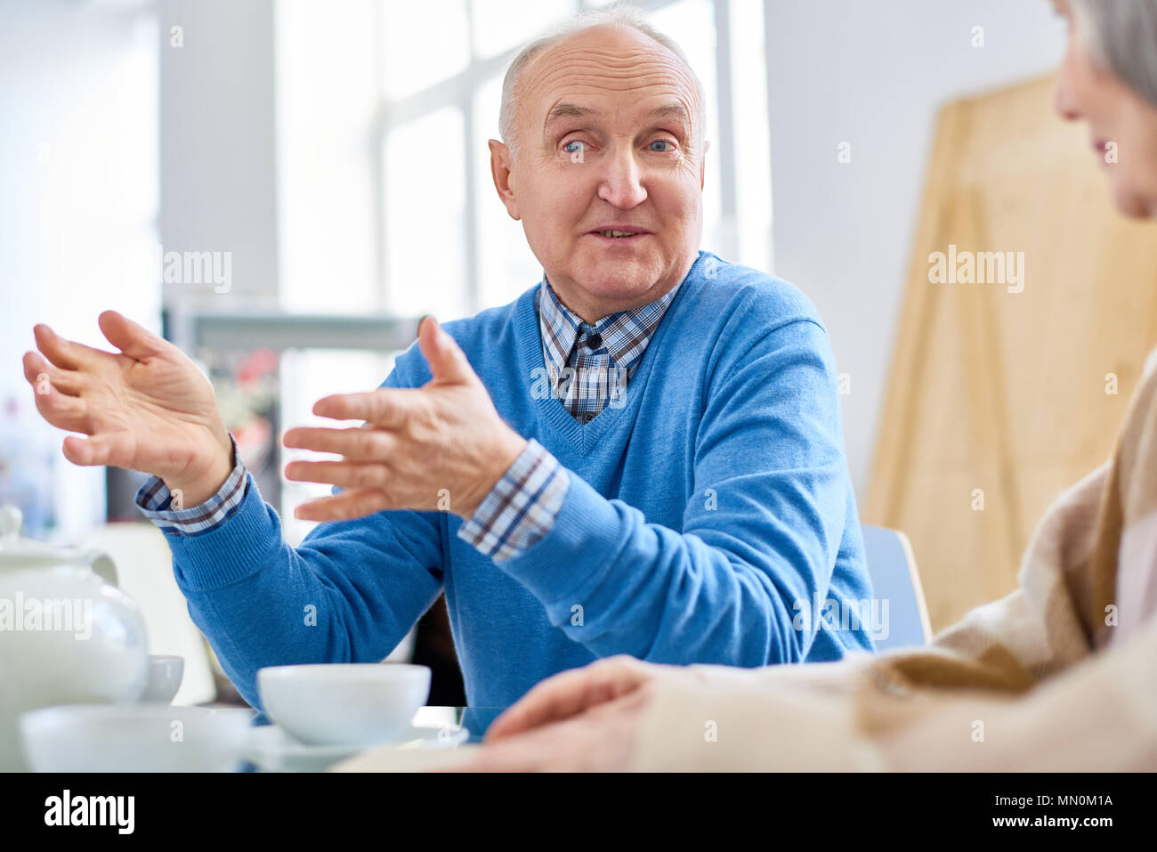 Group of elderly people sitting at table in assisted living home and ...