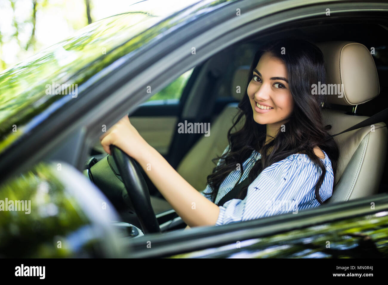 Pretty young woman driving her new car on street Stock Photo - Alamy