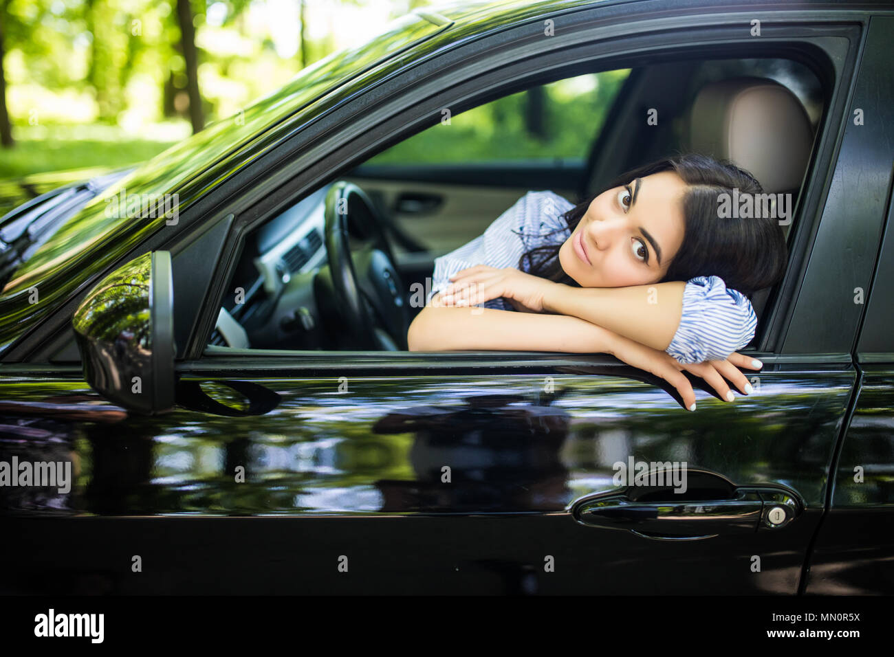 Side view of woman sitting inside a car and looking out of the window ...