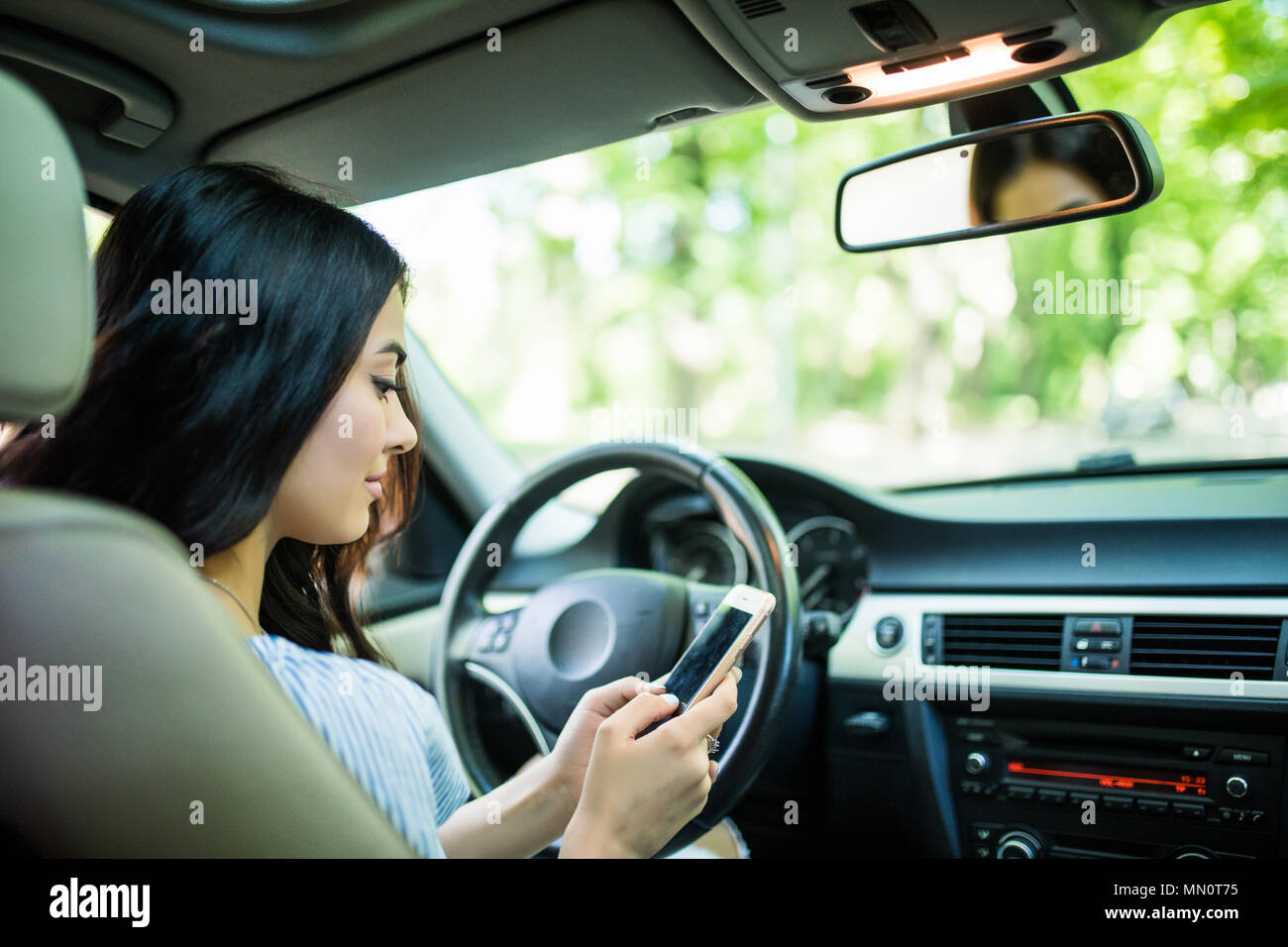 Young woman looking to her smartphone while driving car rear view Stock ...