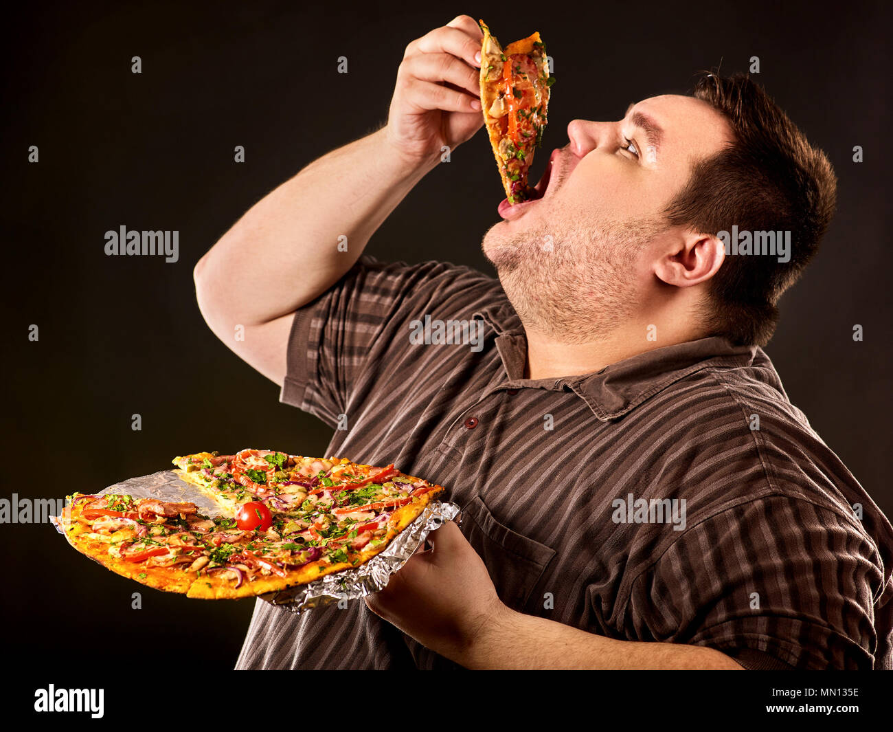 Fat man eating fast food slice pizza . Breakfast for overweight person ...