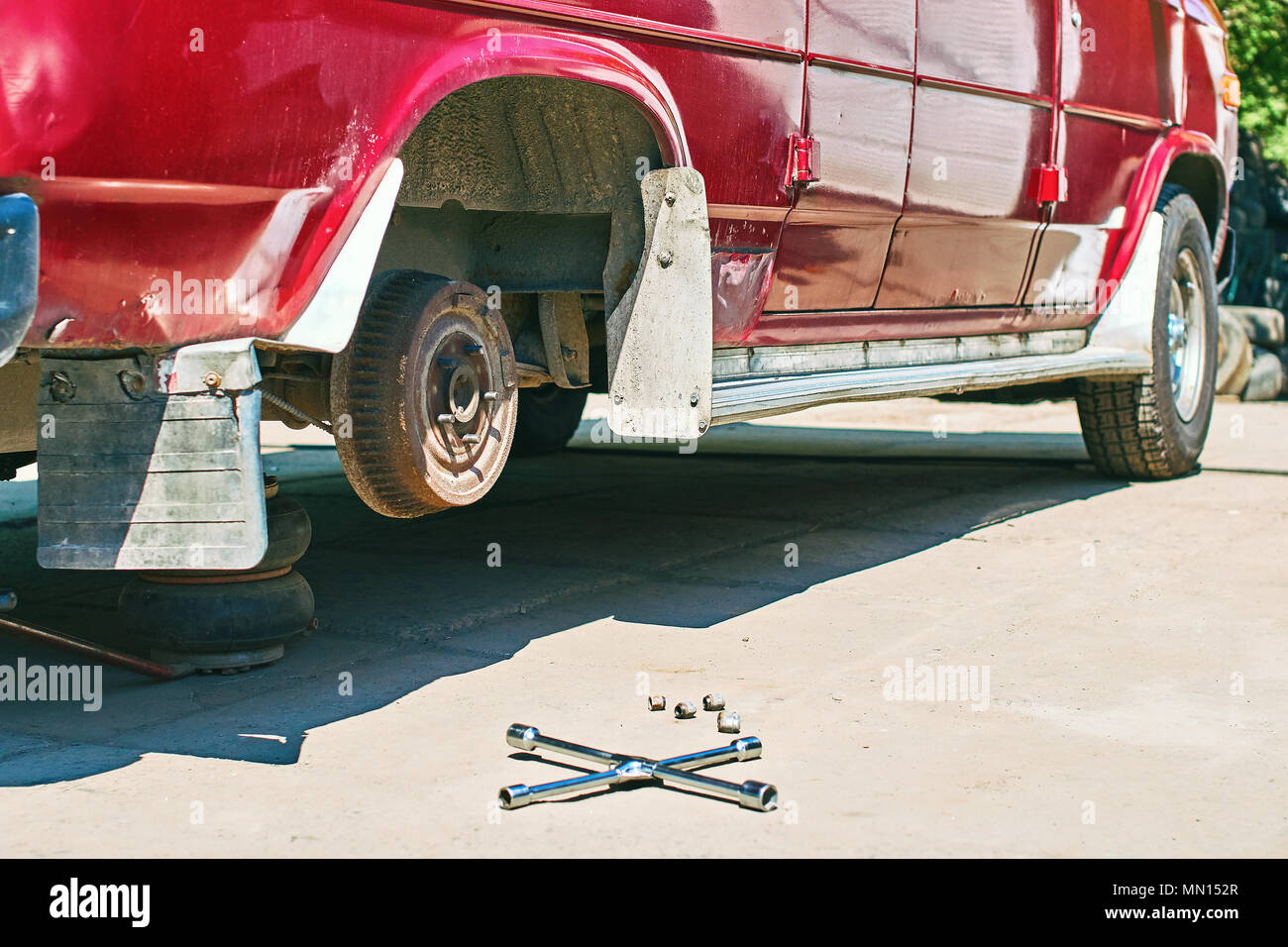 Changing a wheel or tire on an old vintage red van at outdoor car ...