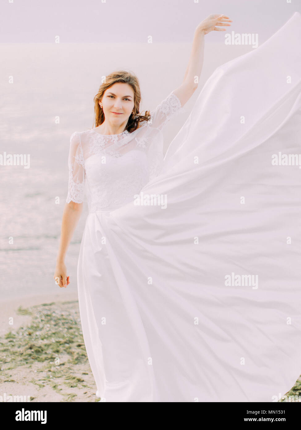 The wedding dress of the bride is fluttering in the wind at the ...