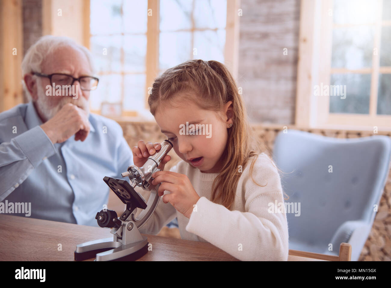 Nice smart girl looking into the microscope Stock Photo - Alamy