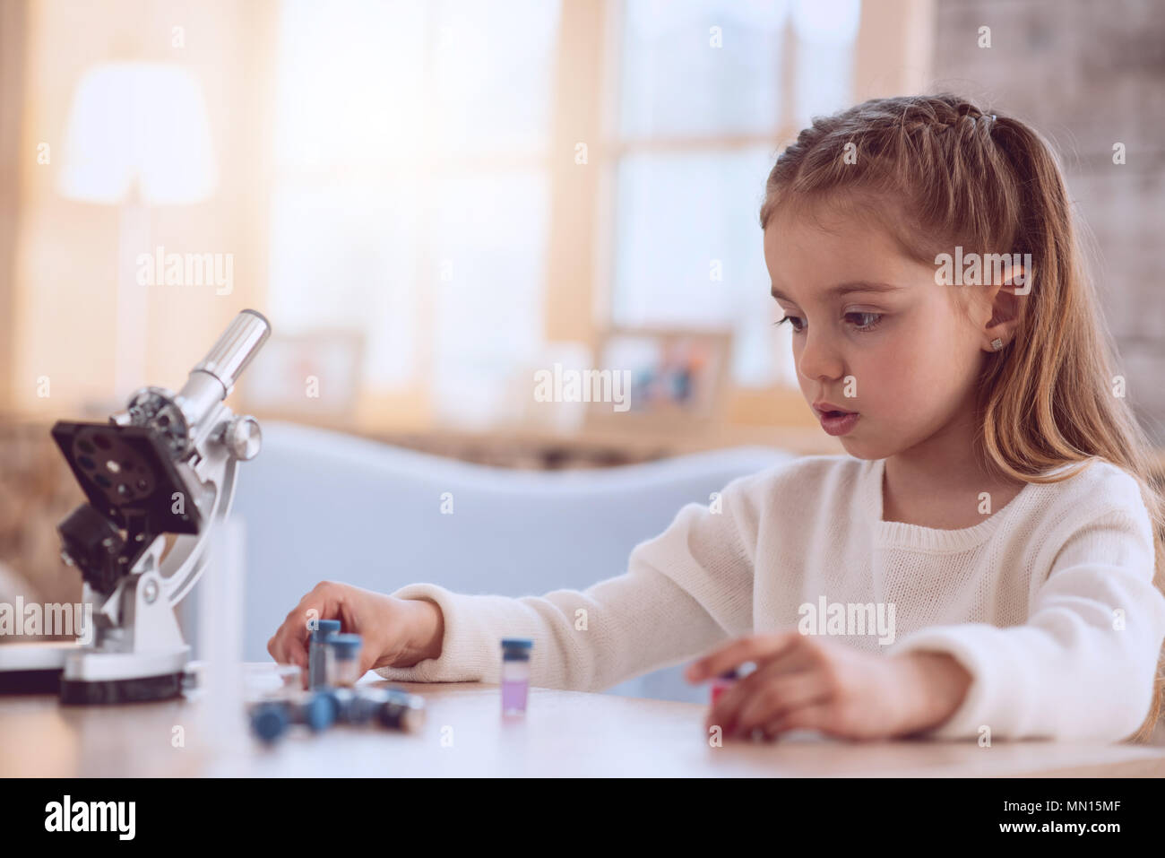 Pleasant cute girl playing with bottles Stock Photo - Alamy