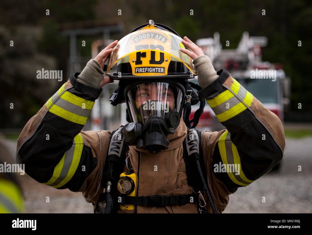 A firefighter from the 23d Civil Engineering Squadron puts his helmet ...