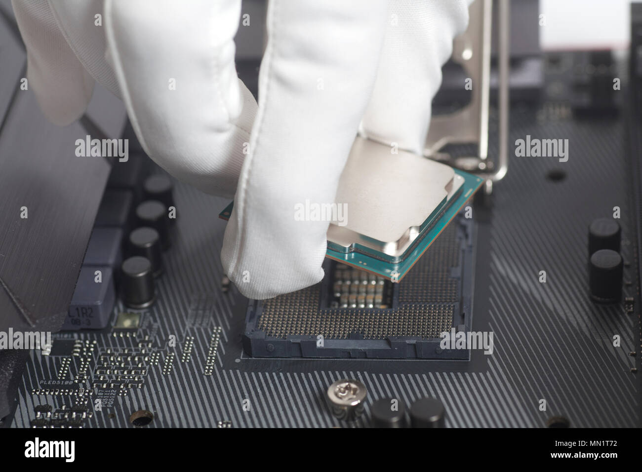 Computer technician wearing white gloves installing CPU into ...
